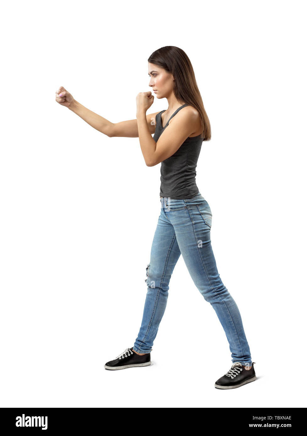 Side view of young attractive woman in gray sleeveless top and blue ...