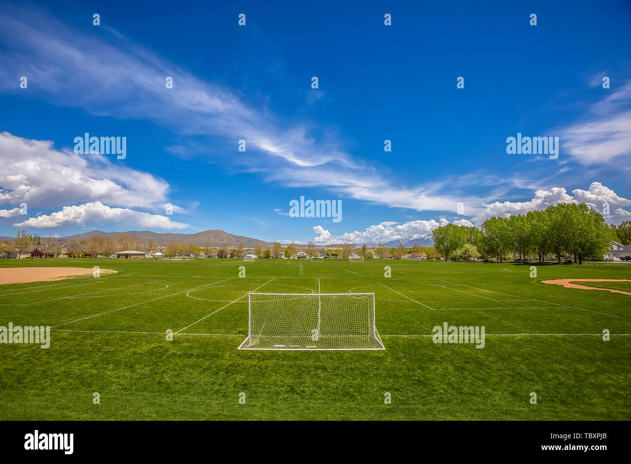 Soccer field with scenic view of towering mountain and vibrant blue sky ...