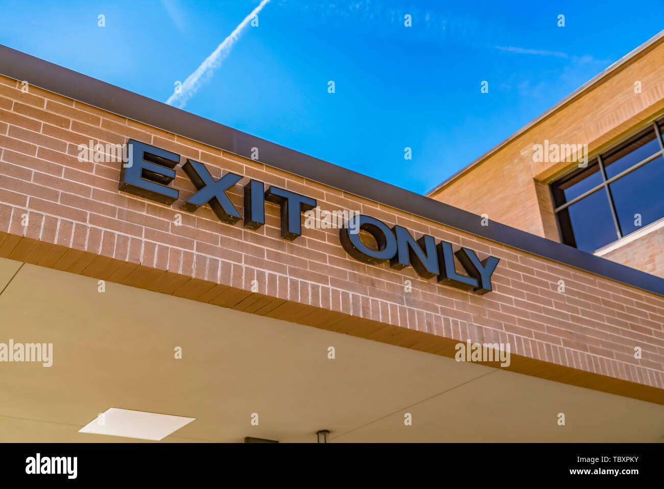 Exit only sign on the exterior brick wall of a building with shiny ...