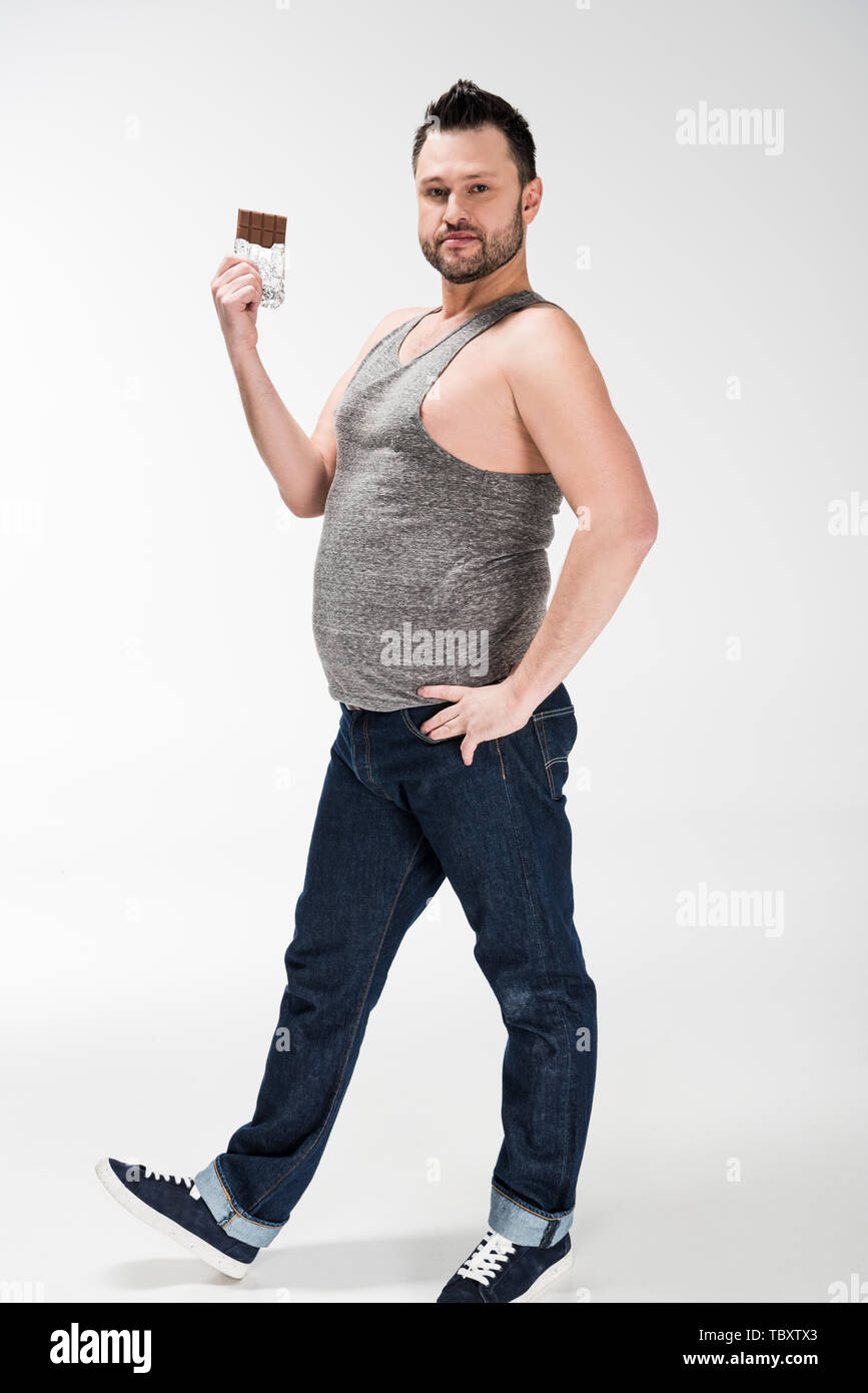 overweight man looking at camera and posing with chocolate on white ...