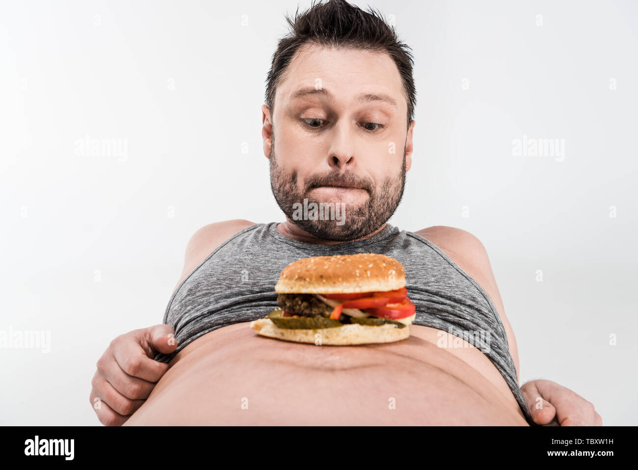 overweight man looking at burger on belly isolated on white Stock Photo ...