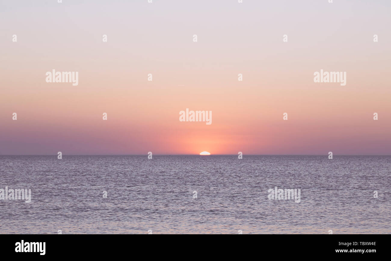 sunset over the horizon of the ocean with cloudless sky Stock Photo - Alamy