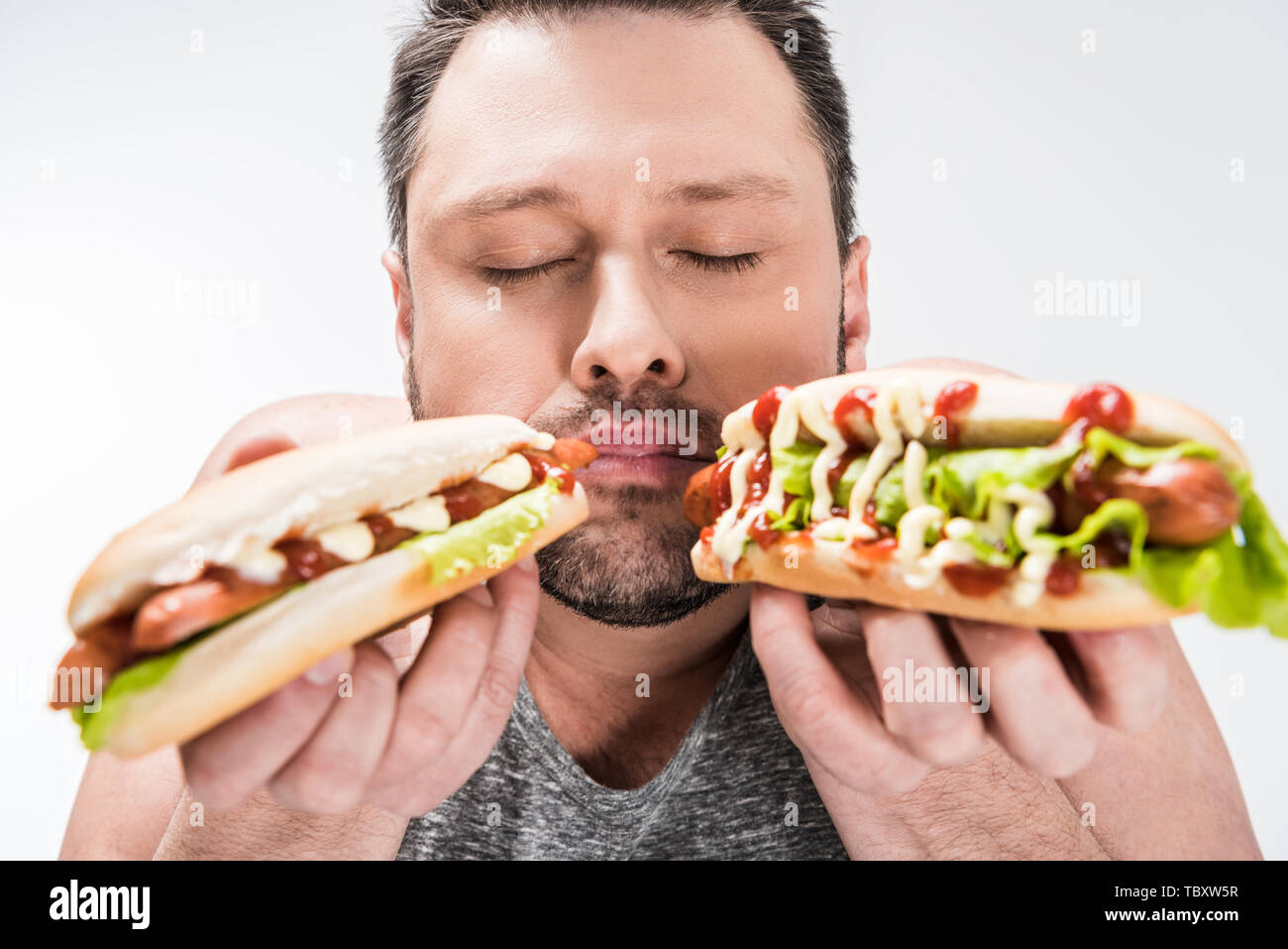overweight man with eyes closed holding delicious hot dogs isolated on ...