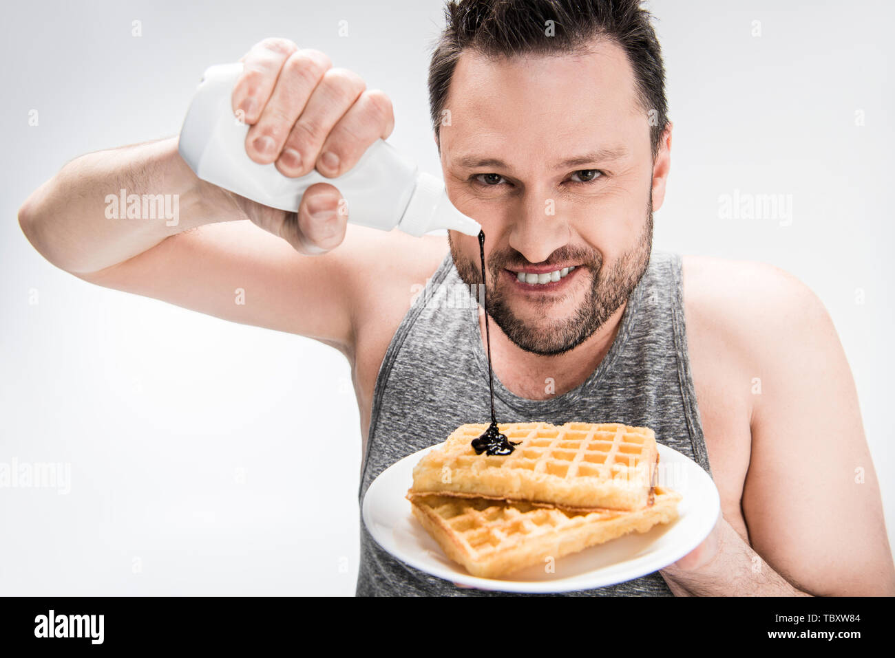 smiling chubby man pouring chocolate syrup on waffles on white Stock ...