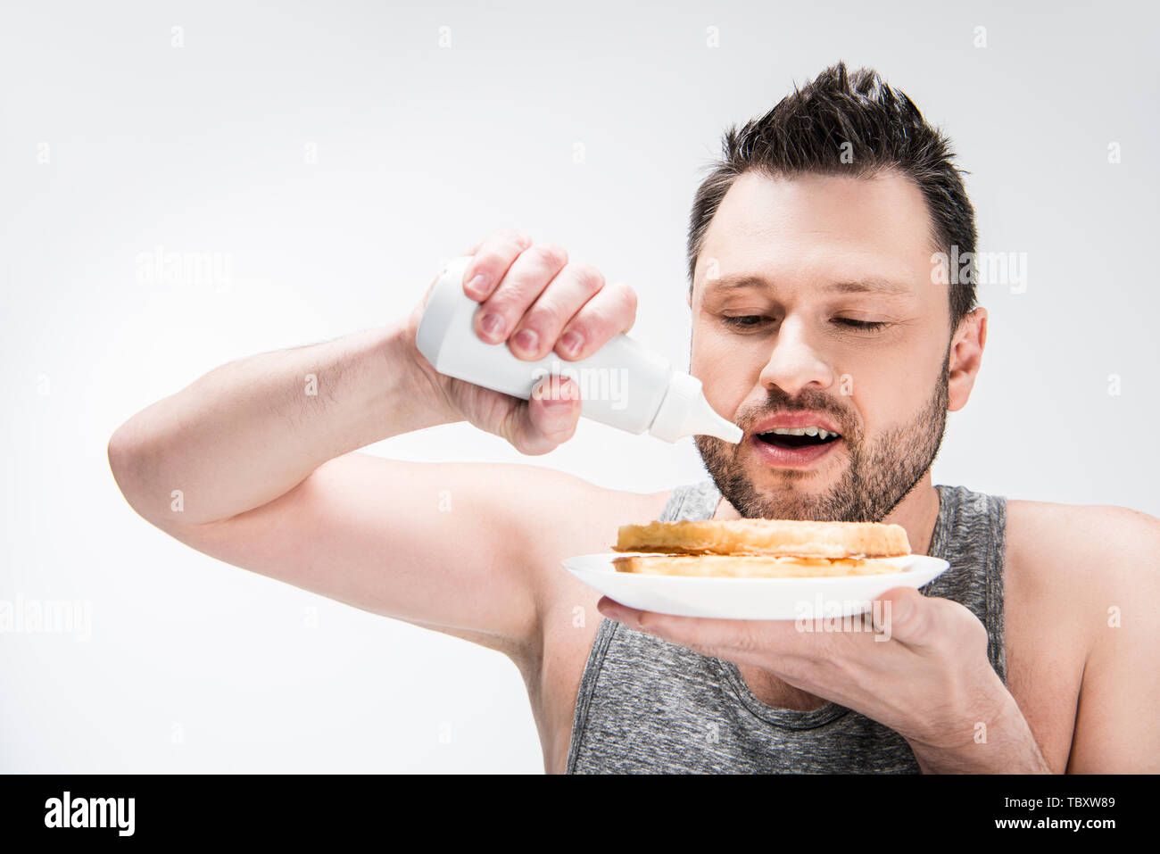 chubby man pouring chocolate syrup on waffles isolated on white Stock ...