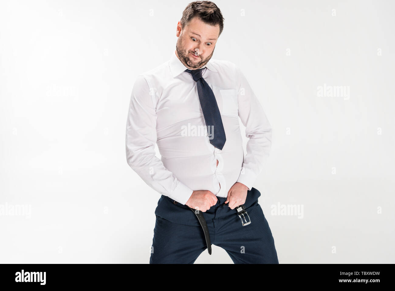 overweight man in formal wear putting on tight pants on white with copy ...