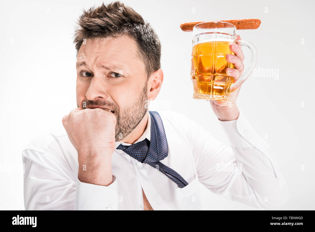 handsome man biting fist and holding glass of beer with sausage ...