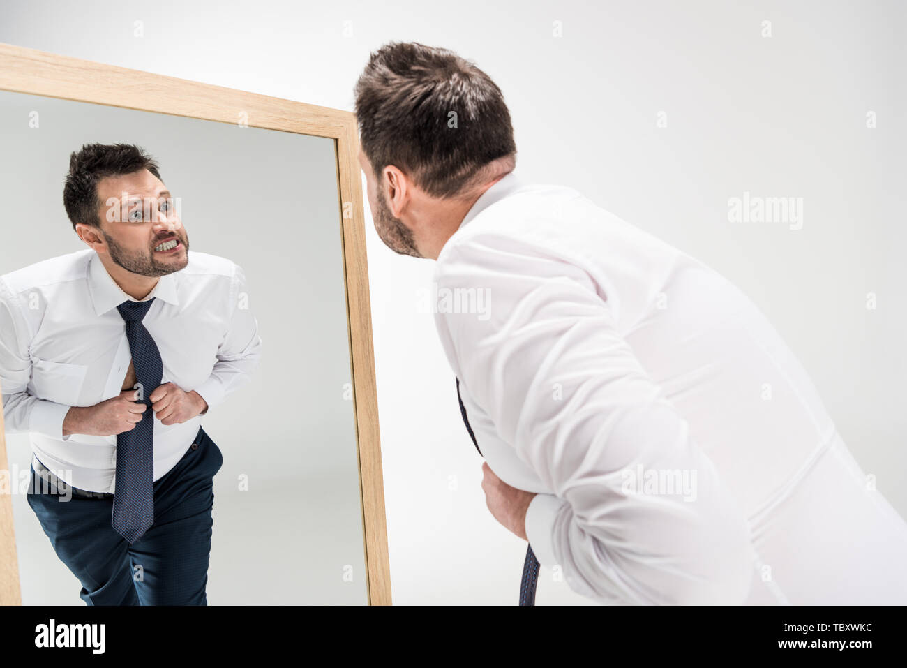 angry overweight man in formal wear looking at reflection in mirror on ...