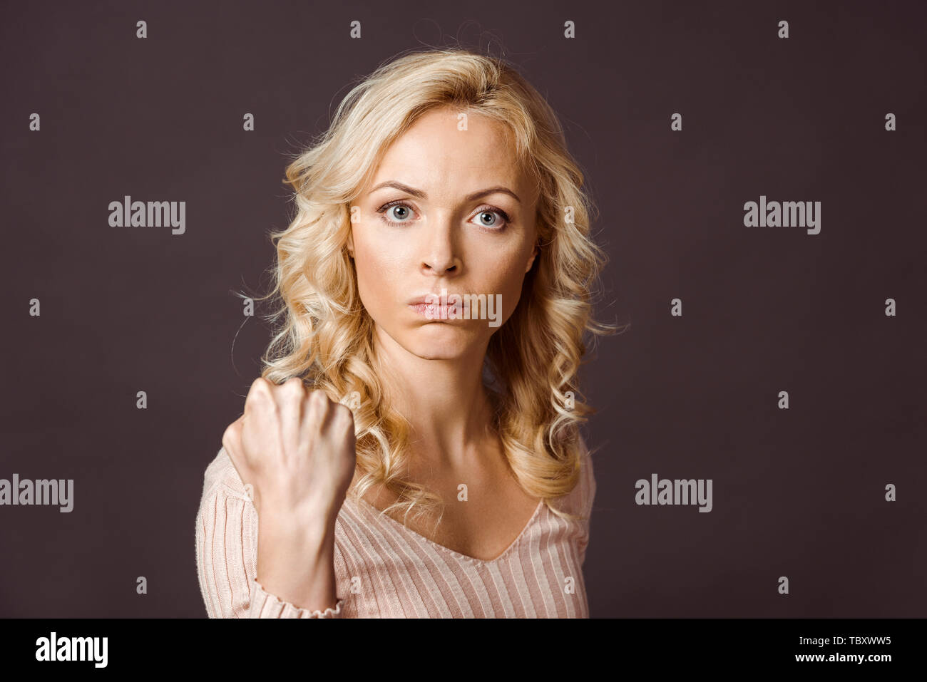 angry blonde woman looking at camera and showing fist isolated on black ...