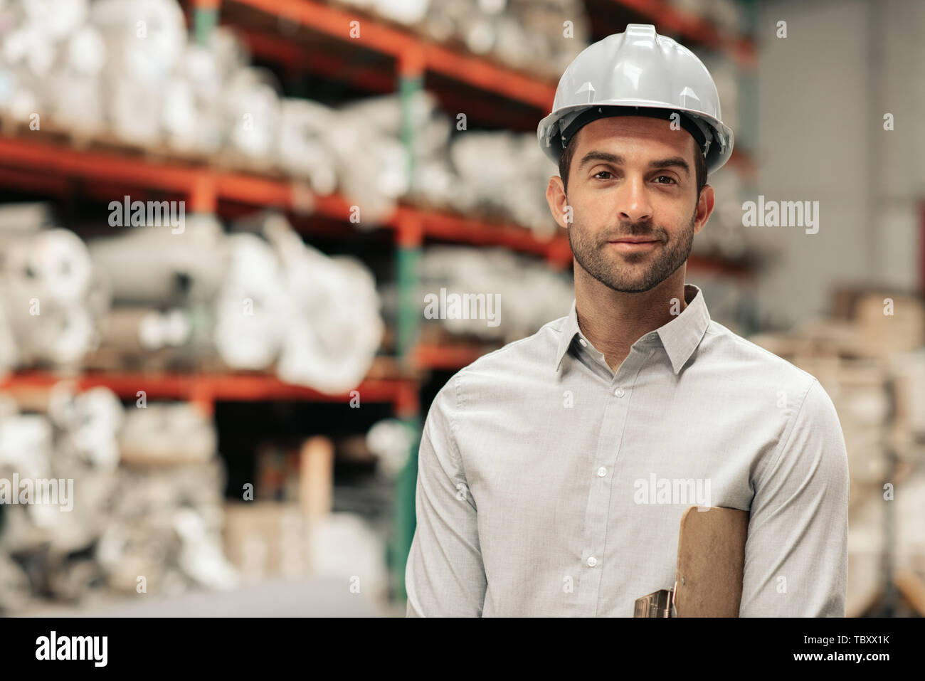 Smiling foreman wearing a hard hat on his warehouse floor Stock Photo ...