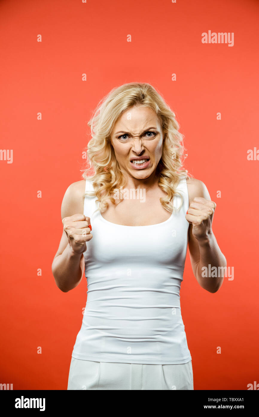angry blonde woman looking at camera and showing fists on red Stock ...