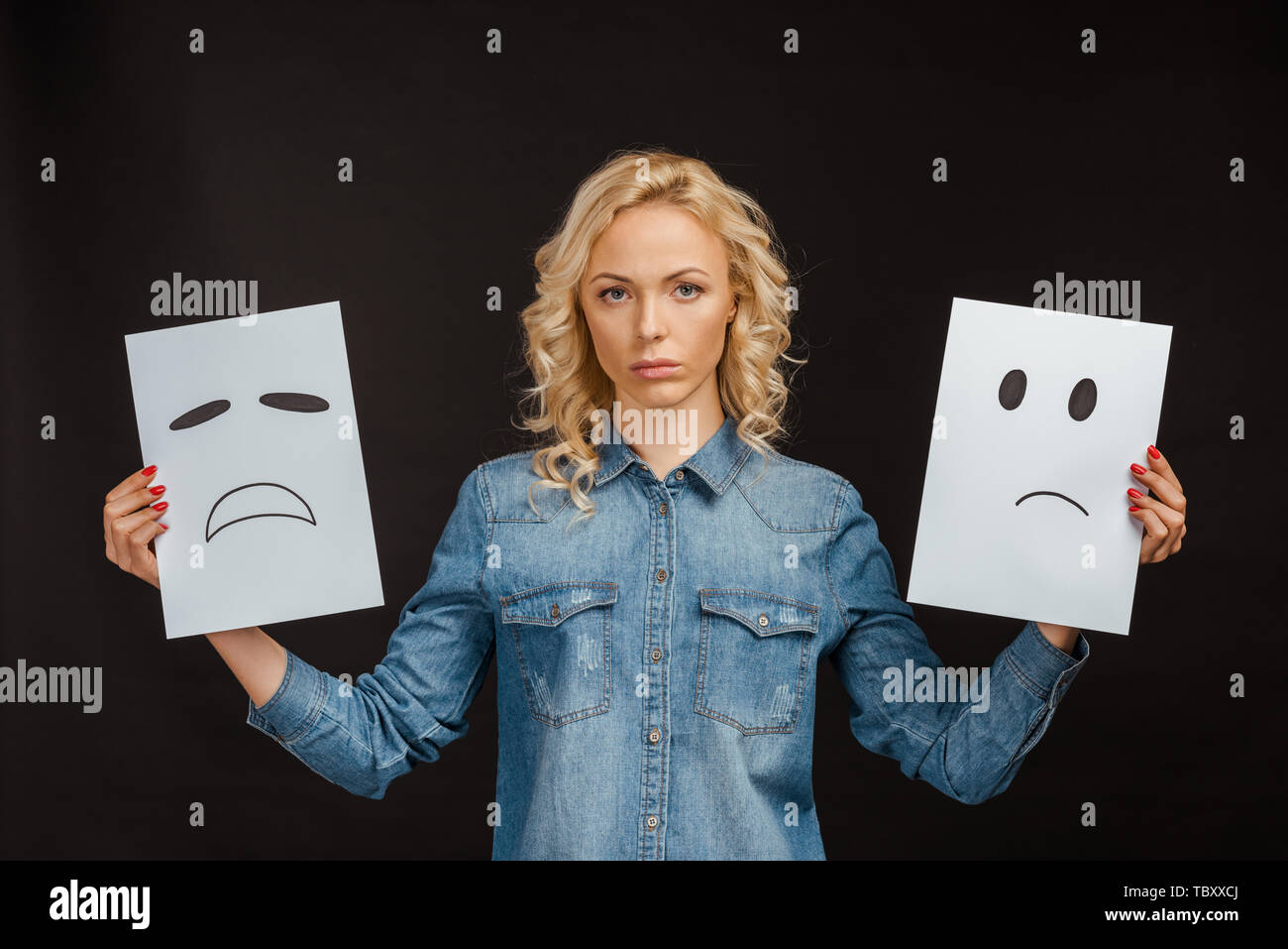upset blonde woman holding cards with sad emotions on black Stock Photo ...