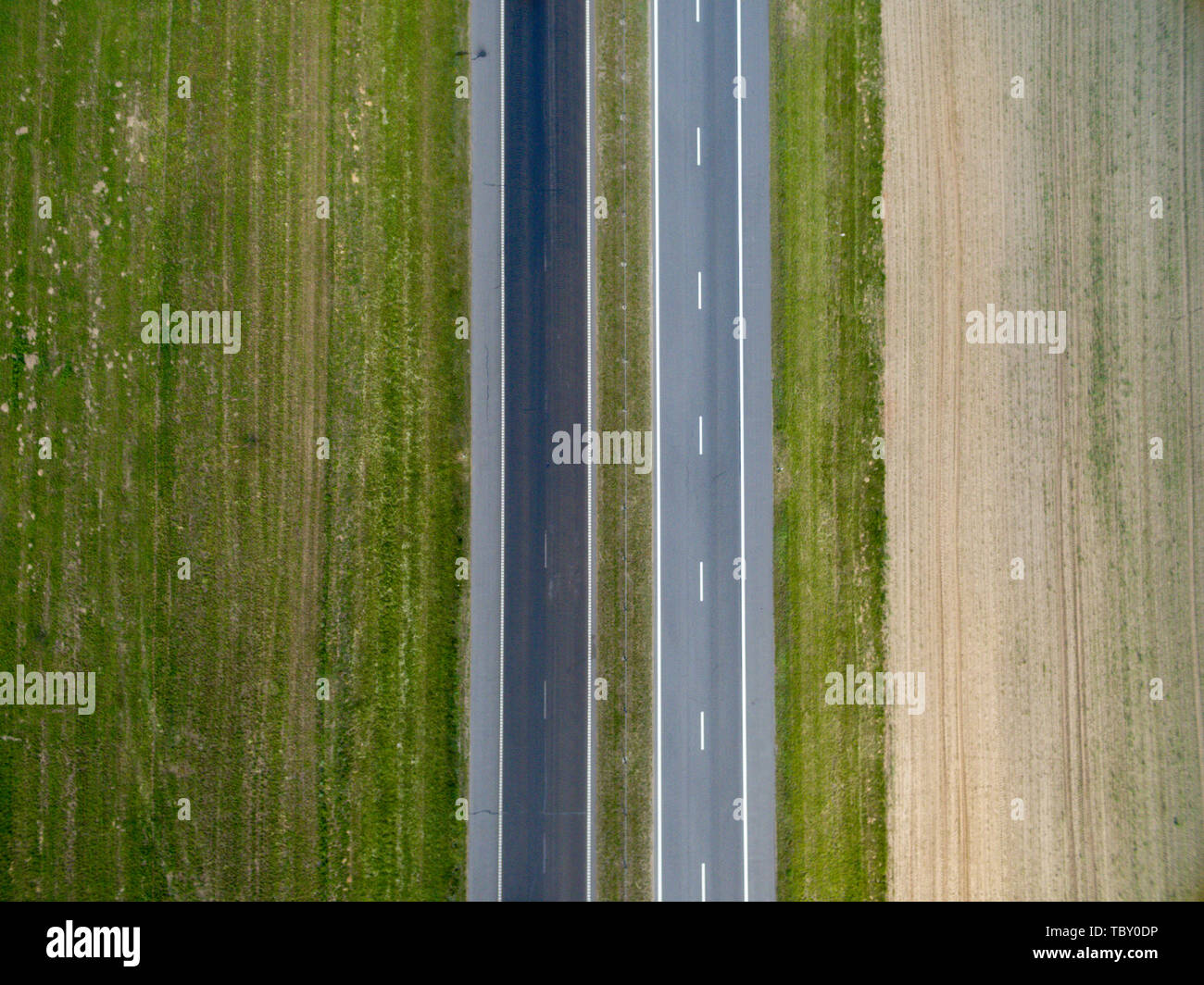 Aerial top view of asphalt road through a green field in summer in ...