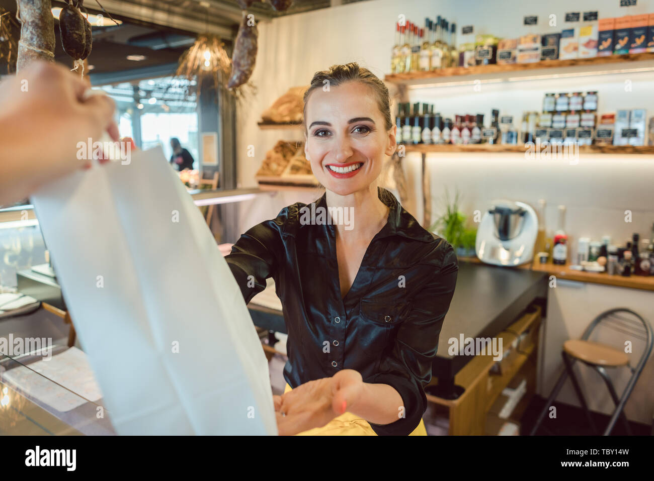 Shop assistant handing over bag with groceries to customer after the ...