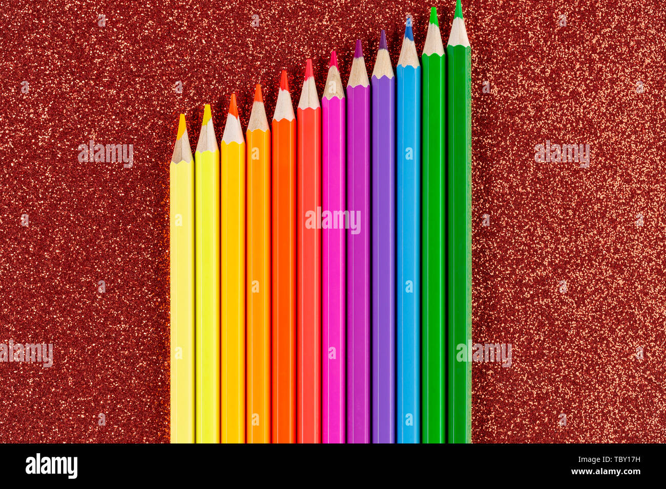 Colored pencils on glitter red background Stock Photo - Alamy