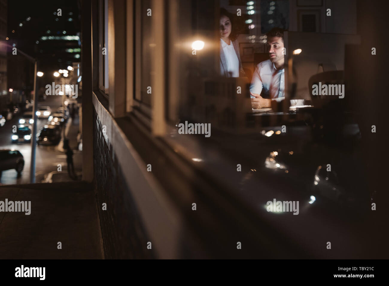 Two businesspeople working late at night inside of an office Stock ...