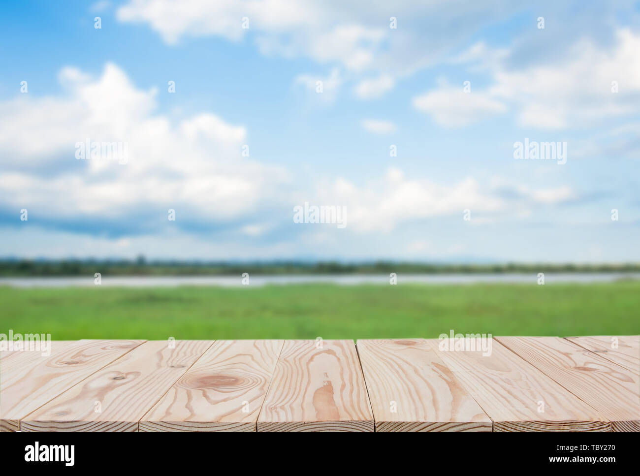 Empty wooden board table top on of blurred blue sky and river ...