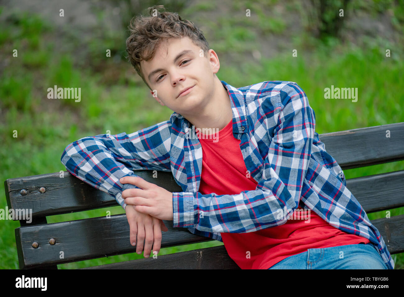 Teen boy sitting on bench Stock Photo - Alamy