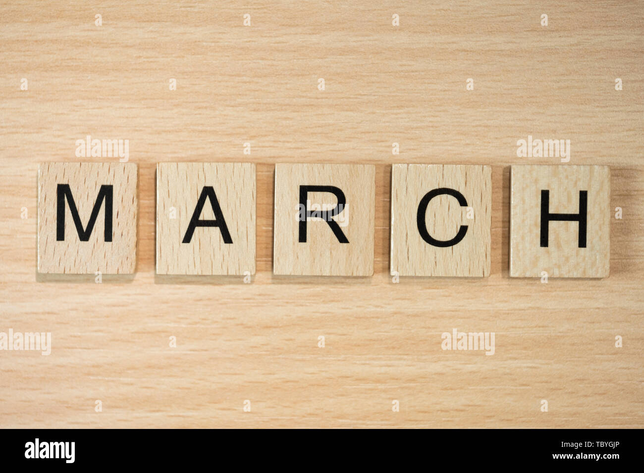 The word March, spelt out using wooden tiles on a wood effect ...