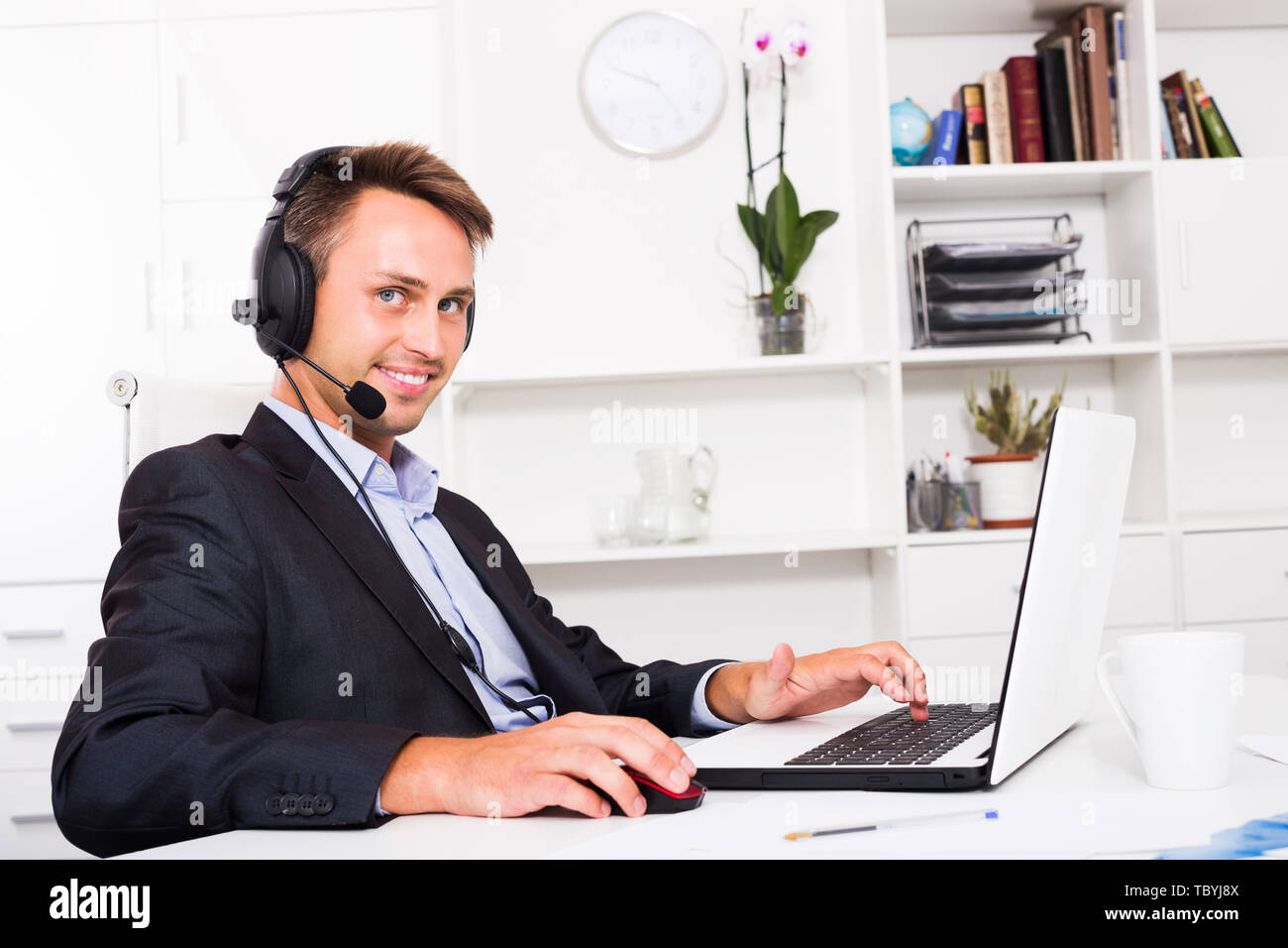 Young smiling male operator with headset on answering at call center ...