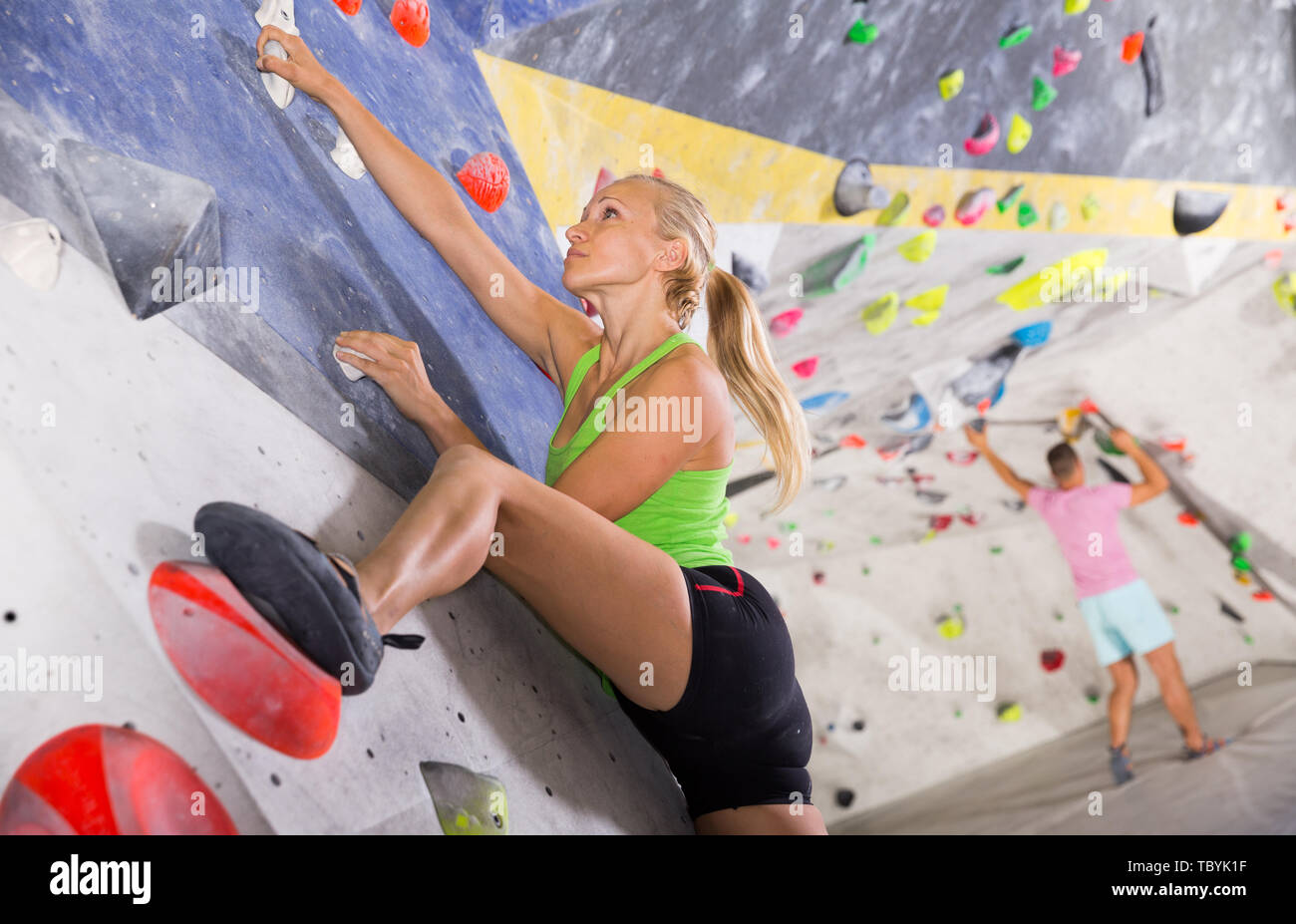 Young sporty woman training at bouldering gym without special climbing ...