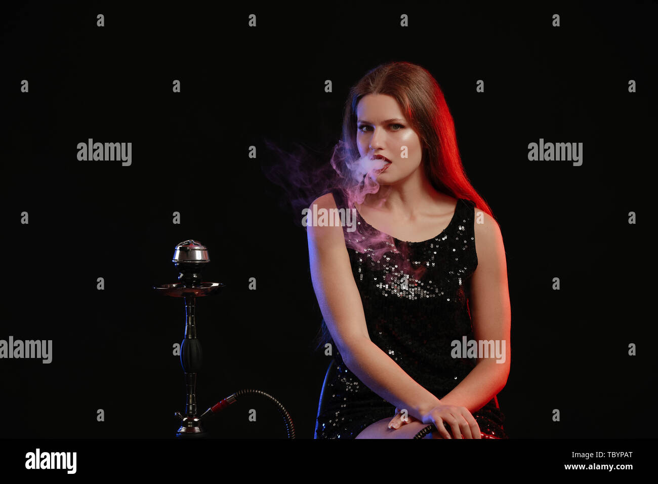 Young woman smoking hookah on dark background Stock Photo - Alamy