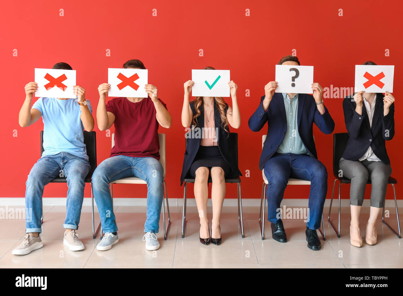 Young people holding paper sheets with different marks while sitting on ...