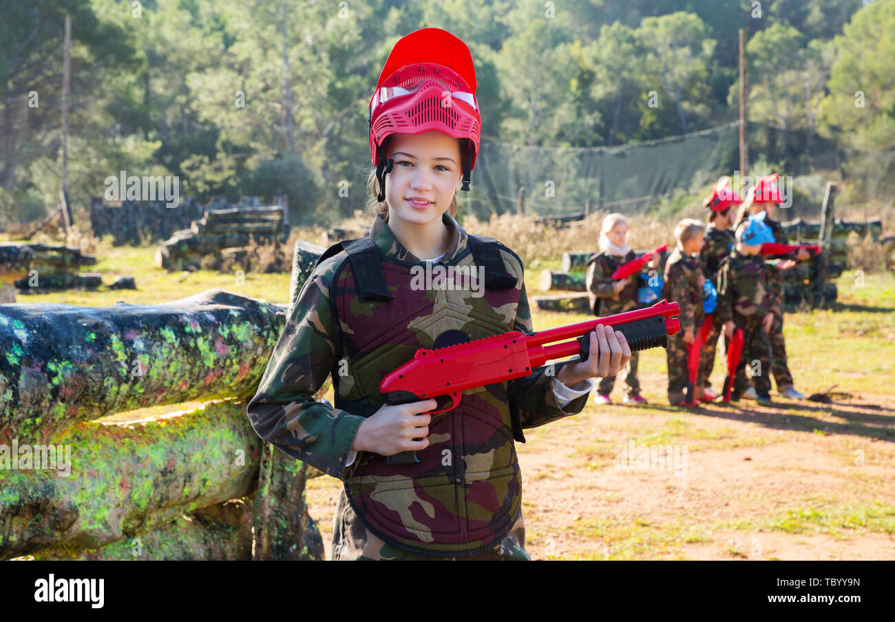 active tweenage girl paintball player in camouflage standing with gun ...