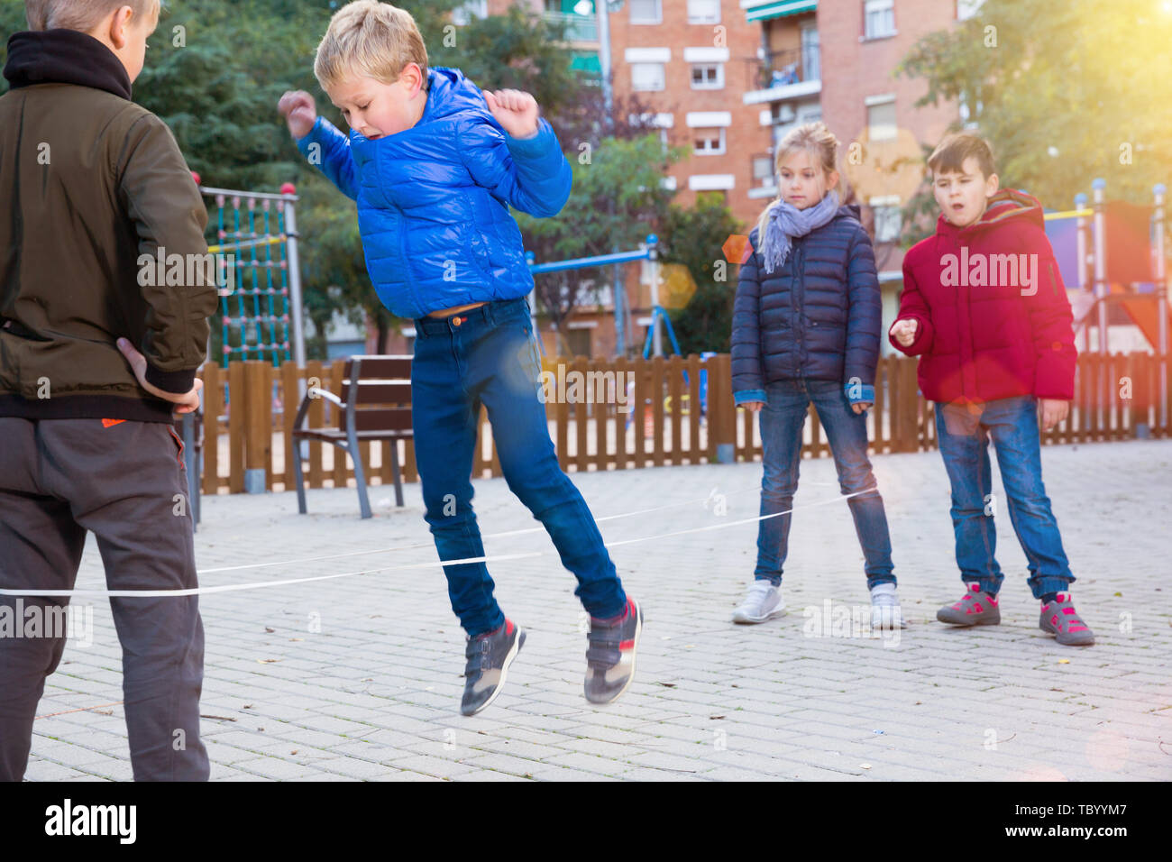 Children active games. Interested happy kids playing chinese jump rope ...