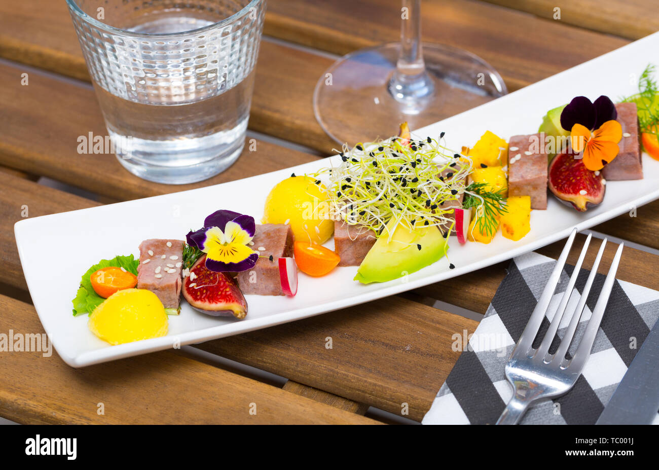 Tasty pan seared tuna served on white plate with avocado, mango and ...