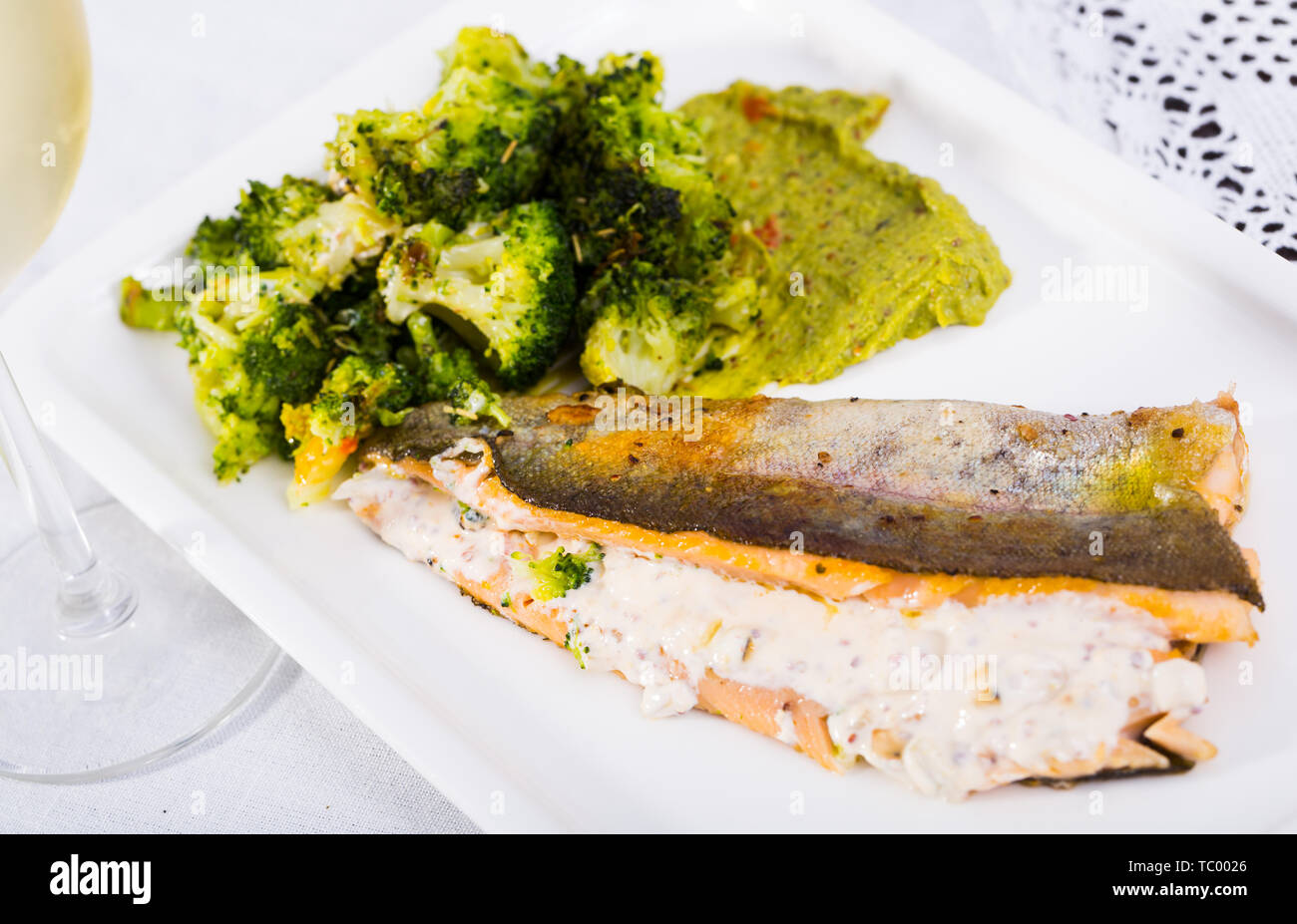 Delicious fried brook trout fillets with broccoli served with glass of ...
