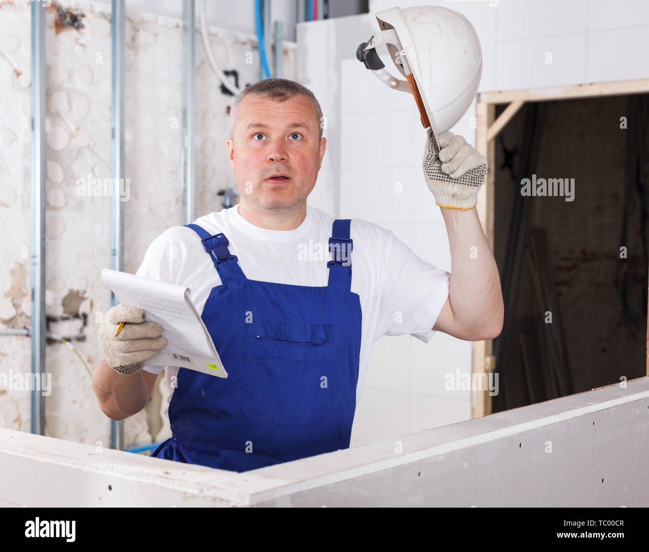 Scared and confused male contractor looking at room and determining ...