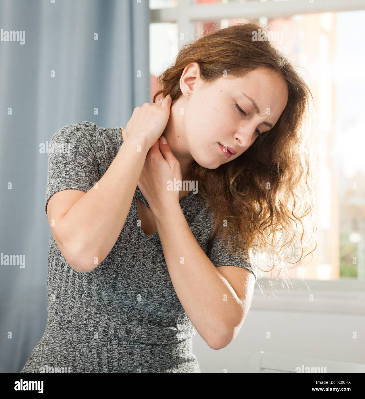Portrait of girl suffering from neck pain standing at living room Stock ...
