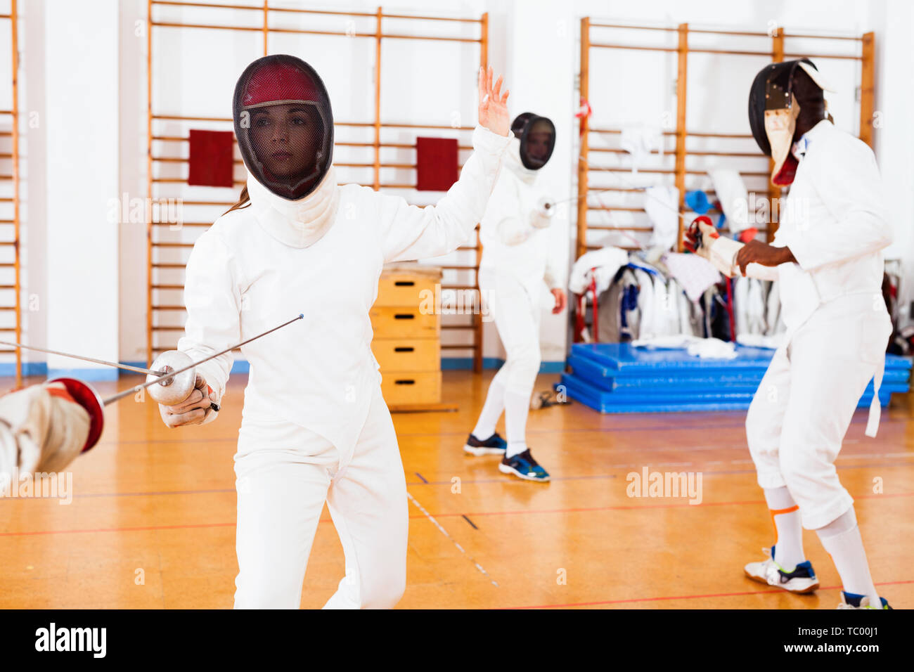 Two glad cheerful positive smiling female fencers exercising movements ...