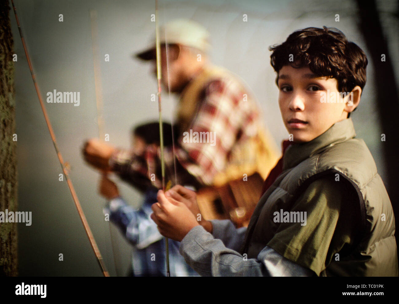 Portrait of a boy holding a fishing rod while out fishing with his ...