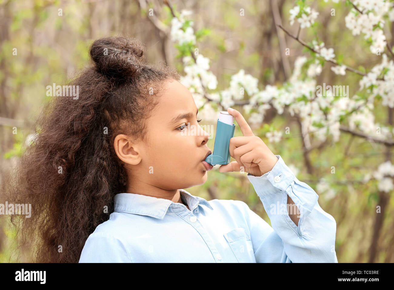 African-American girl with inhaler having asthma attack outdoors on ...