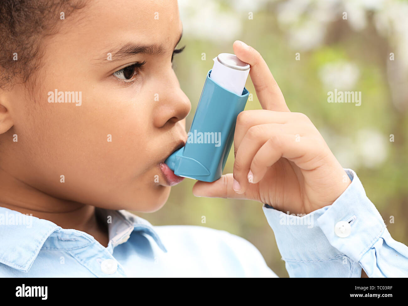 African-American girl with inhaler having asthma attack outdoors on ...