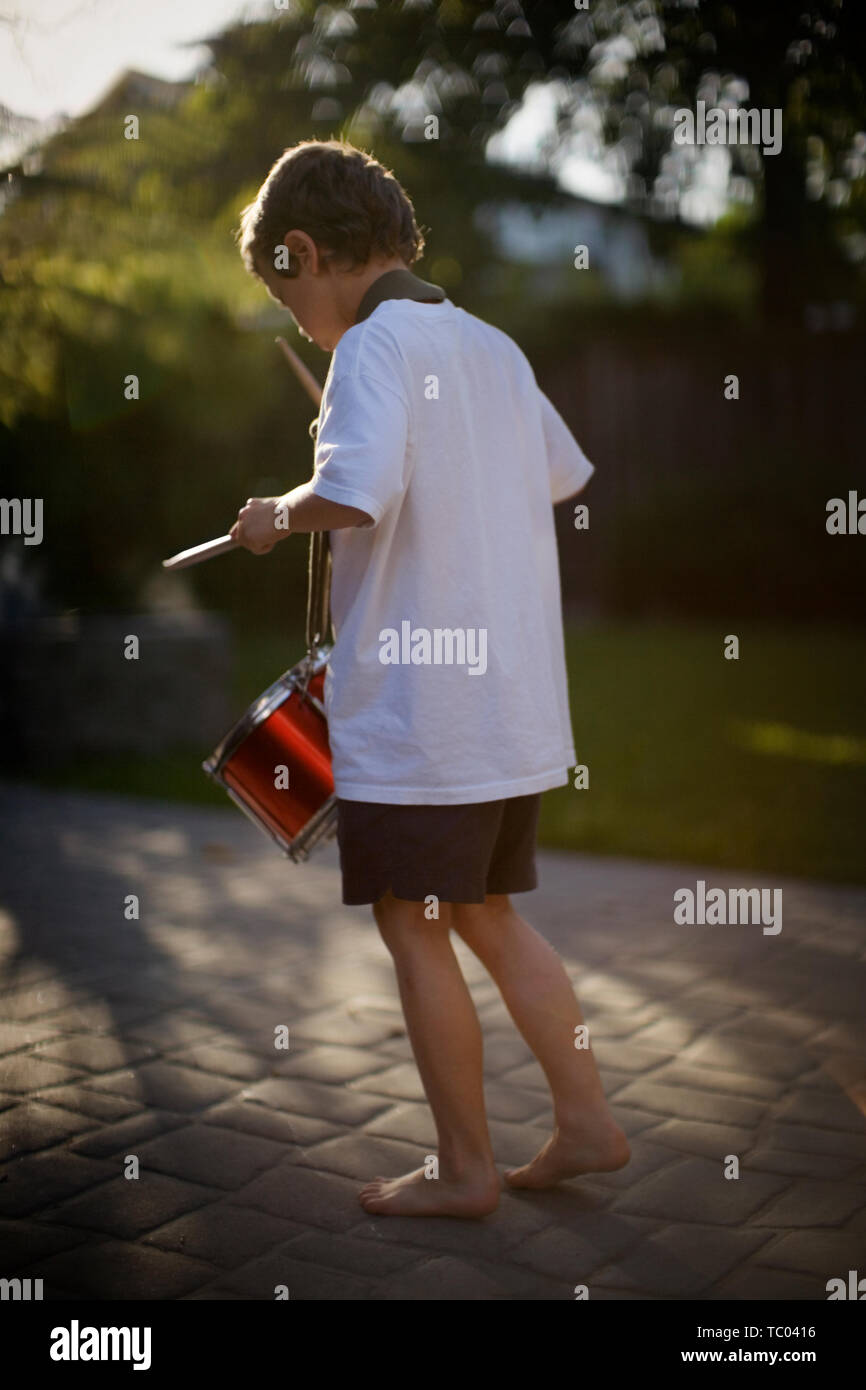 Young boy playing a drum while walking Stock Photo - Alamy