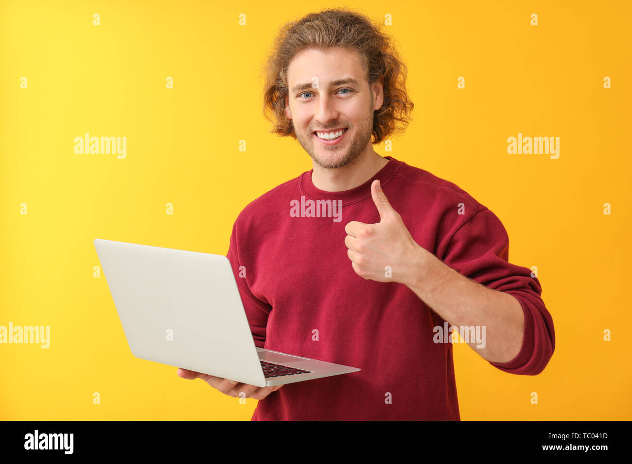 Male programmer with laptop showing thumb-up gesture on color ...