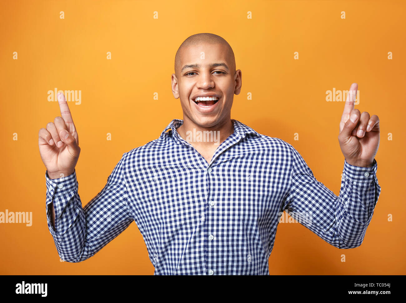 Handsome African-American man pointing at something on color background ...