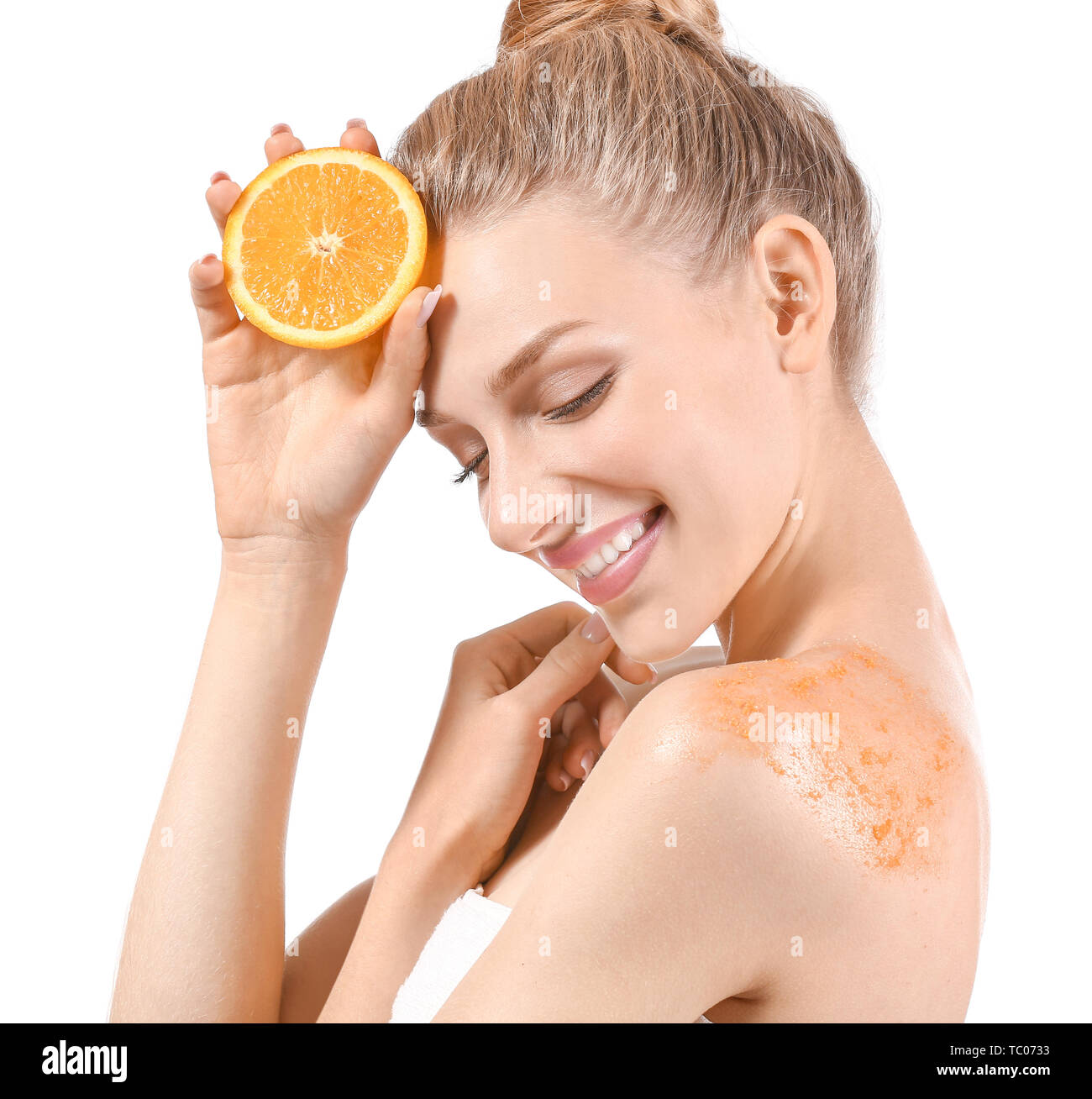 Young woman with orange body scrub on her body against white background ...
