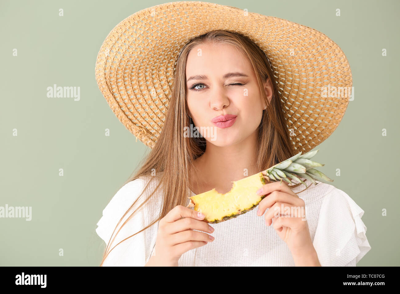 Beautiful young woman eating pineapple on color background Stock Photo ...