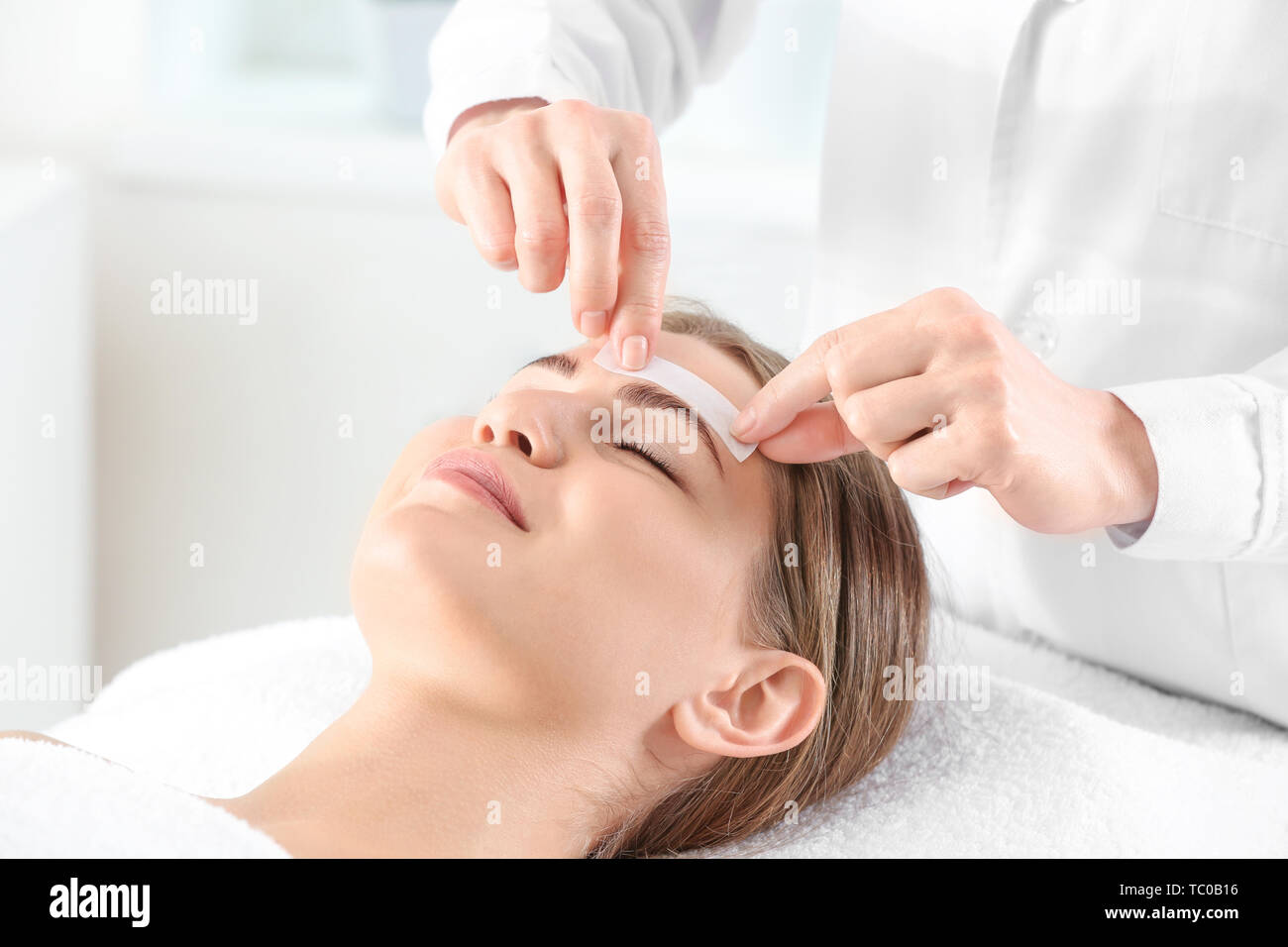 Young woman undergoing eyebrows epilation in beauty salon Stock Photo ...