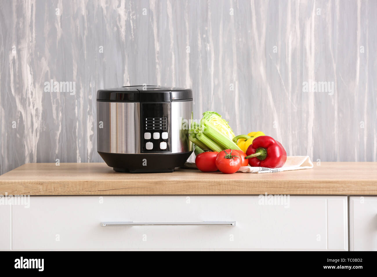 Modern multi cooker with vegetables on kitchen table Stock Photo - Alamy