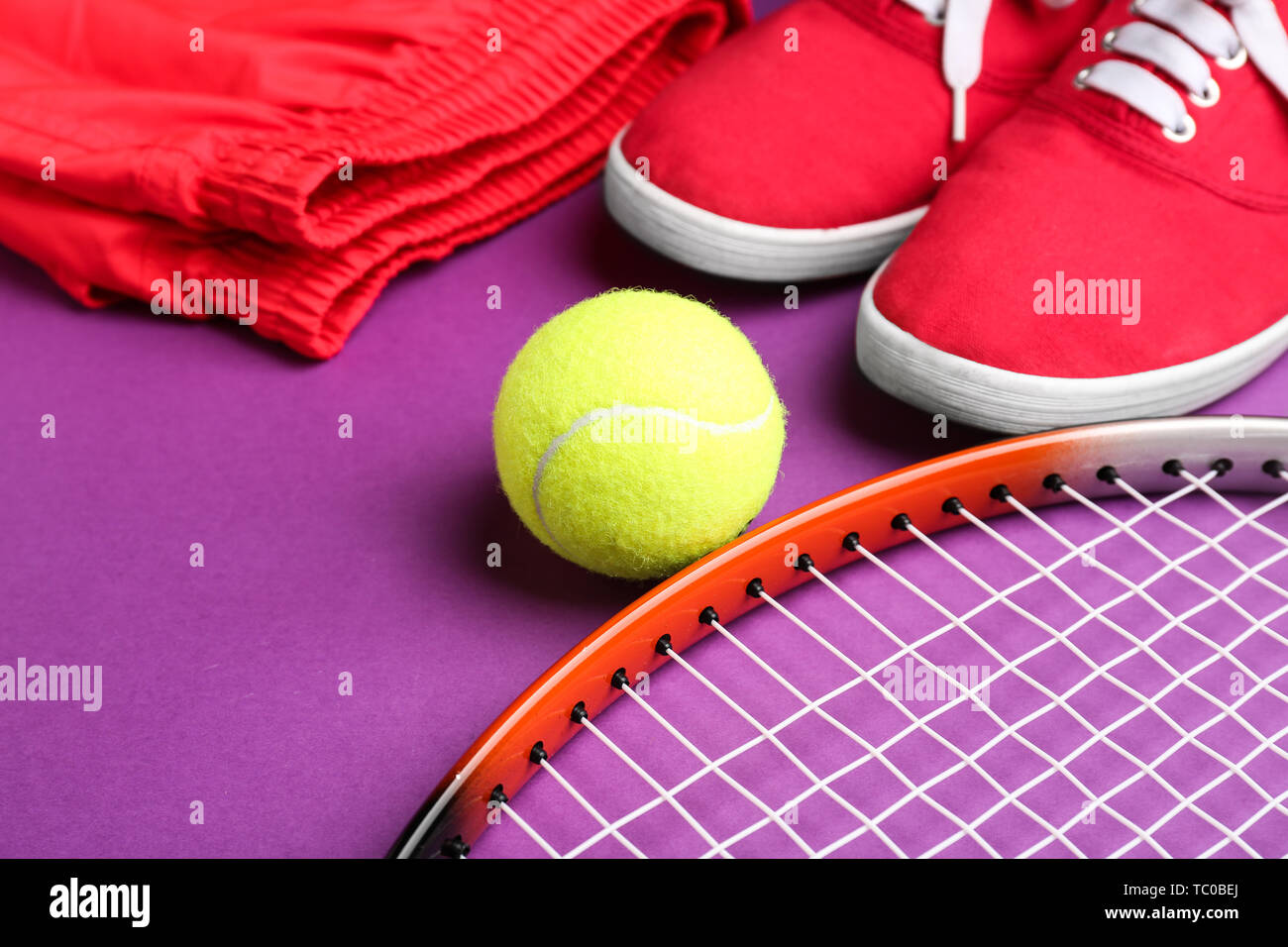 Tennis racket, shoes, clothes and ball on color background, closeup ...