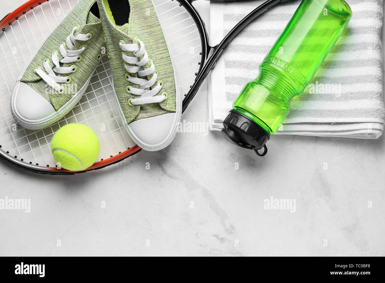 Tennis racket, shoes, towel, bottle of water and ball on light ...