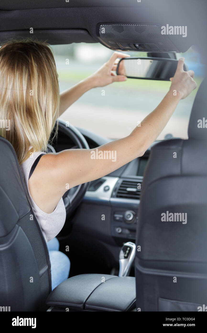 young woman driver adjusting her rearview mirror in the car Stock Photo ...