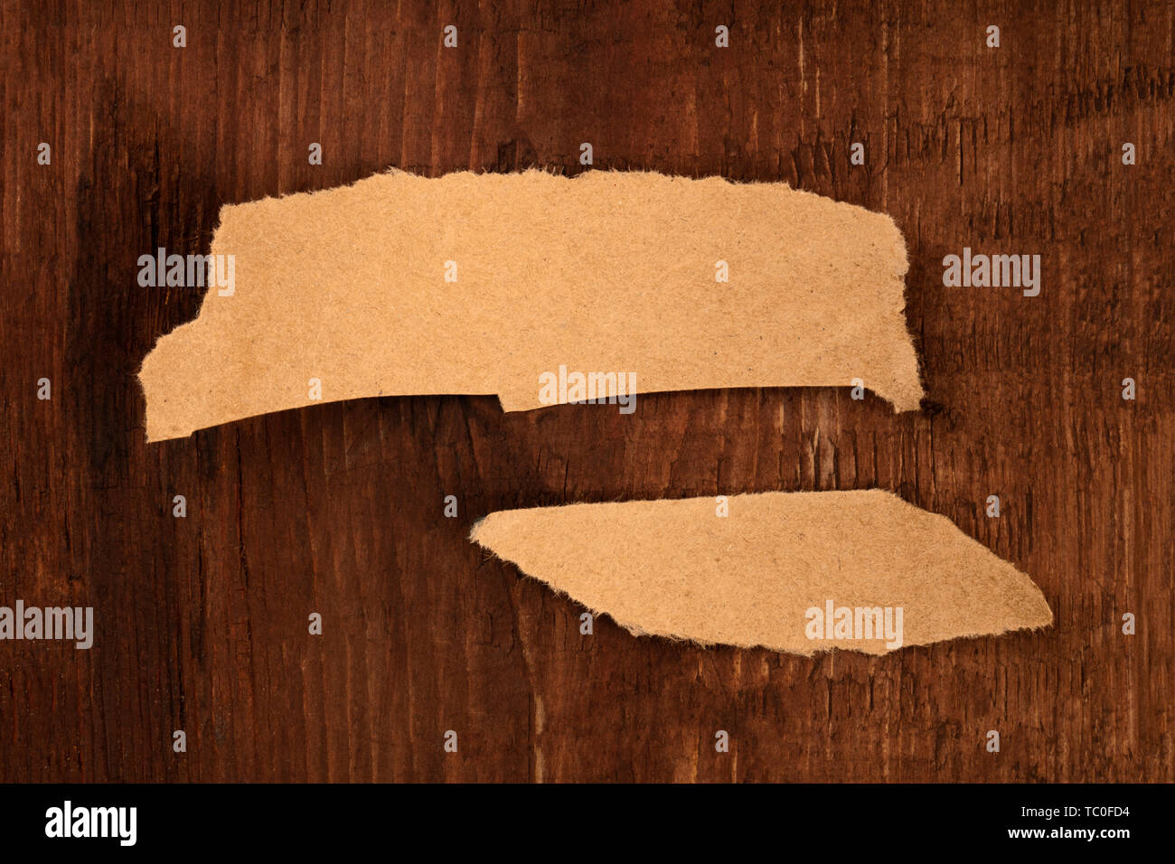 Two pieces of torn brown craft paper, shot from above on a dark rustic ...