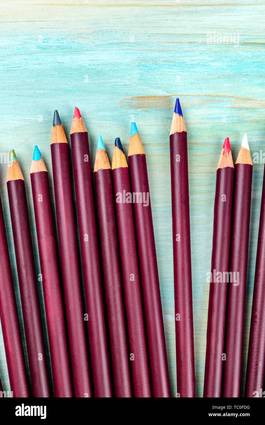An overhead photo of colored pencils on a vibrant teal blue background ...