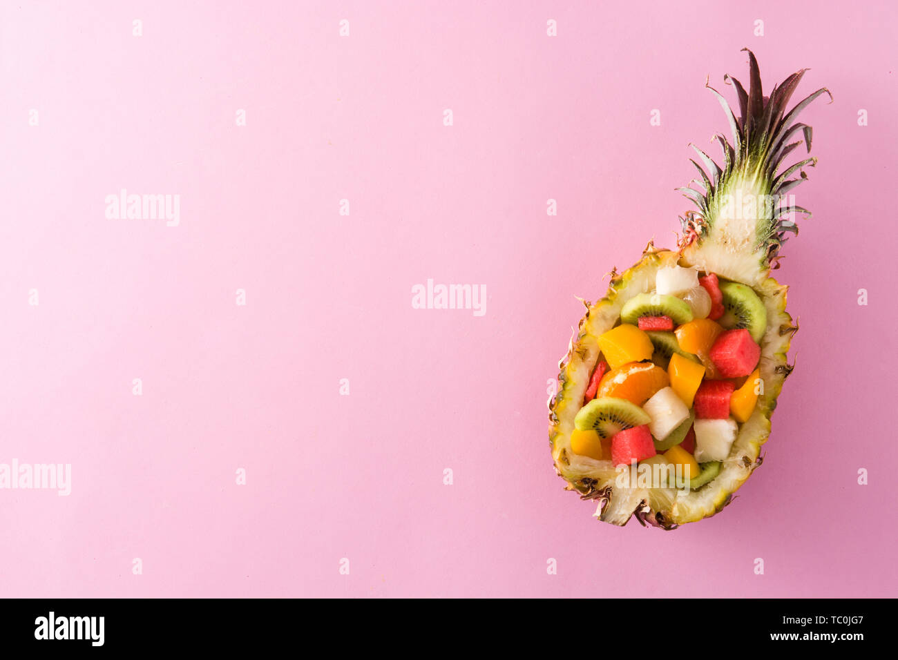Mix fruit served inside pineapple on pink background Stock Photo - Alamy